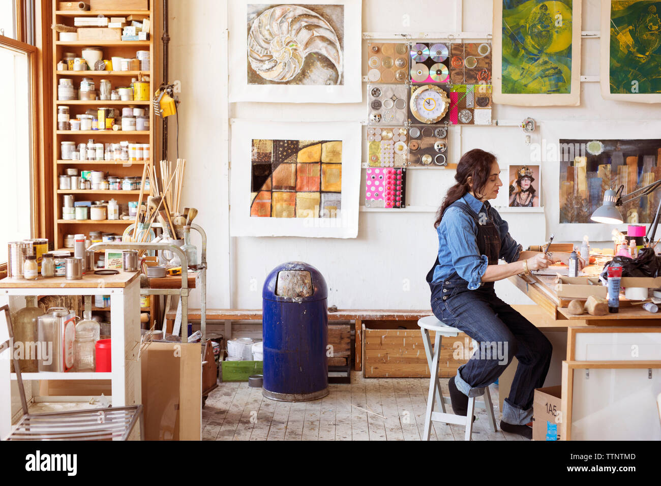 Side view of artist working at table in workshop Stock Photo - Alamy