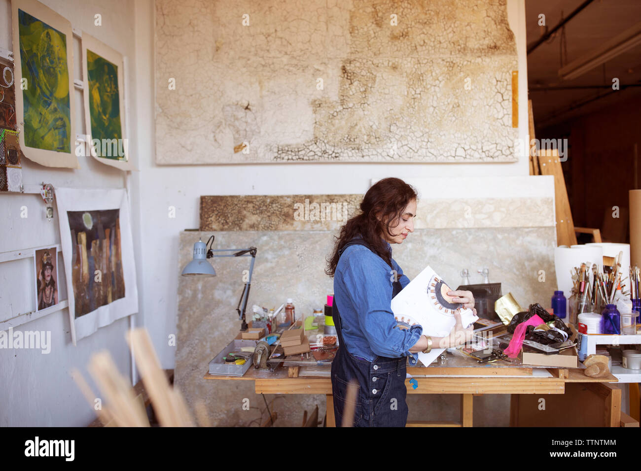 Side view of artist holding artwork by table in workshop Stock Photo ...