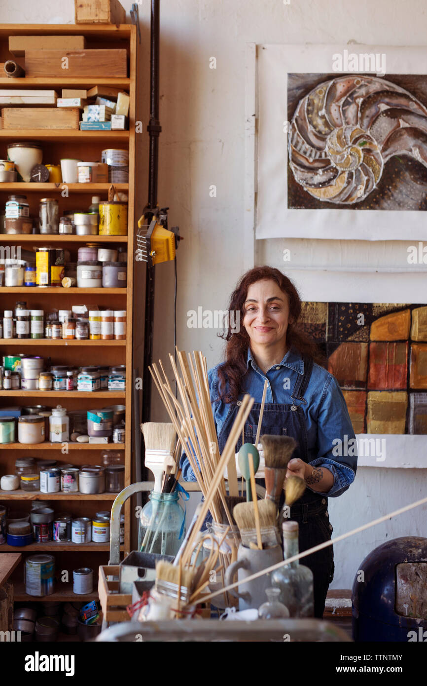 Portrait of smiling artist standing by shelf in workshop Stock Photo ...