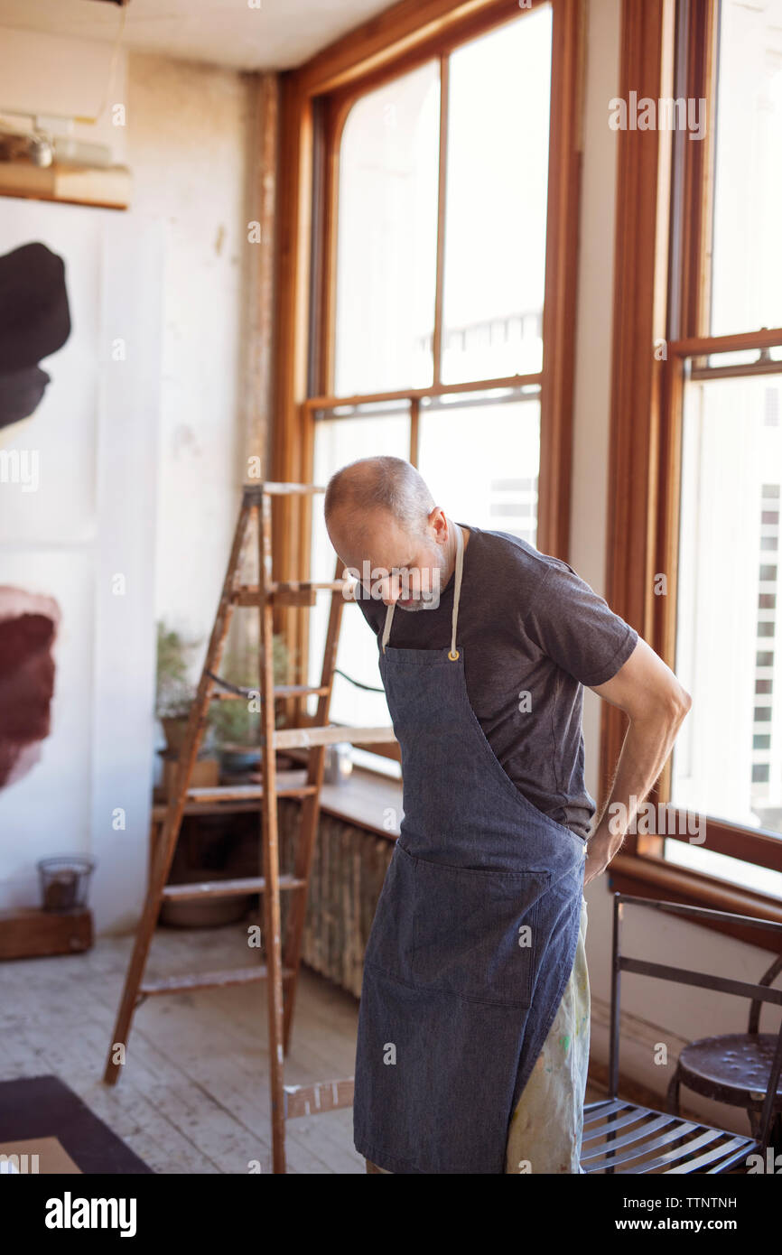 Artist wearing apron by window in workshop Stock Photo - Alamy
