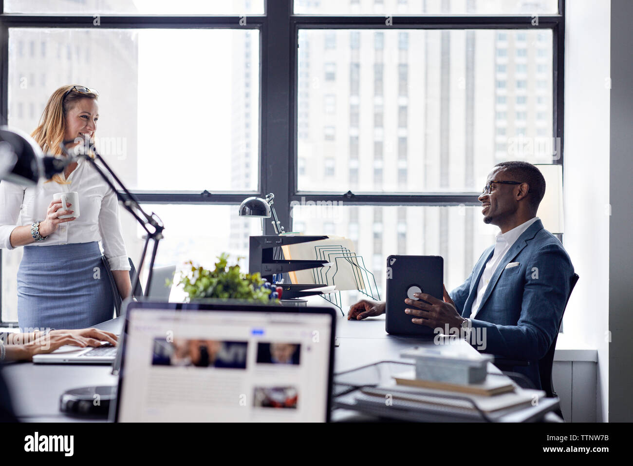 business people talking while working against window in office Stock ...
