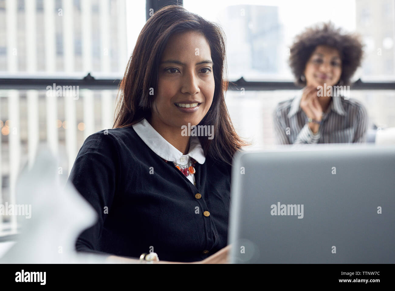 businesswoman using laptop computer while working against window in ...