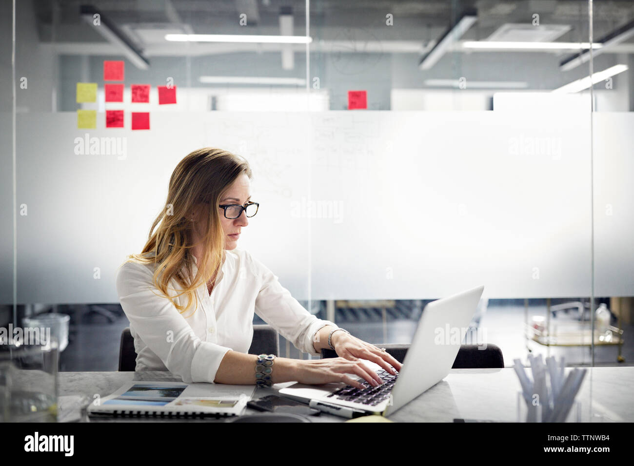 Serious businesswoman using laptop computer while working in office ...