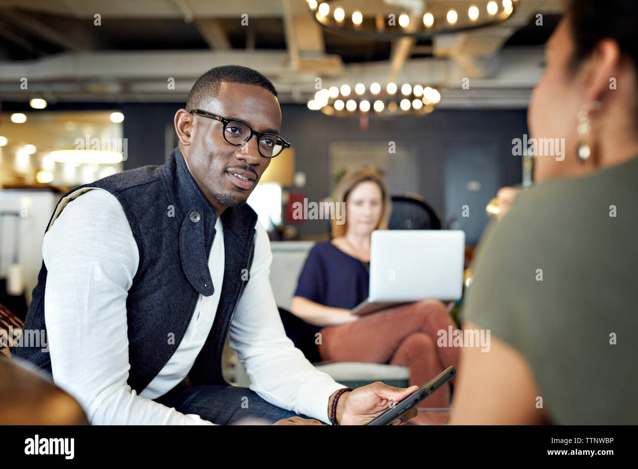 business people talking with female colleague using laptop computer in ...