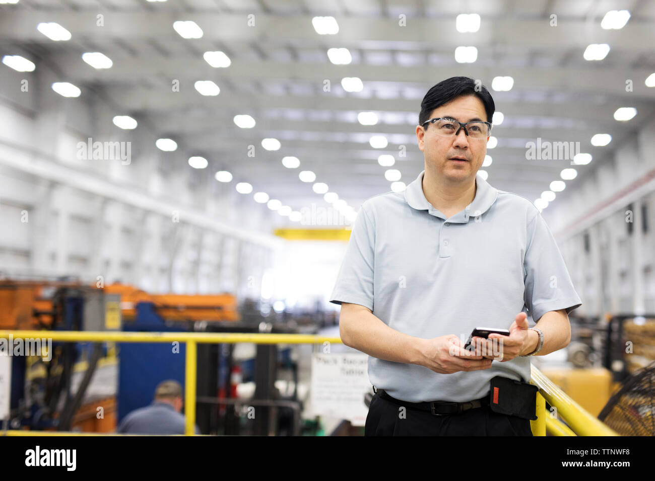 Supervisor holding smart phone while standing in Steel Industry Factory ...