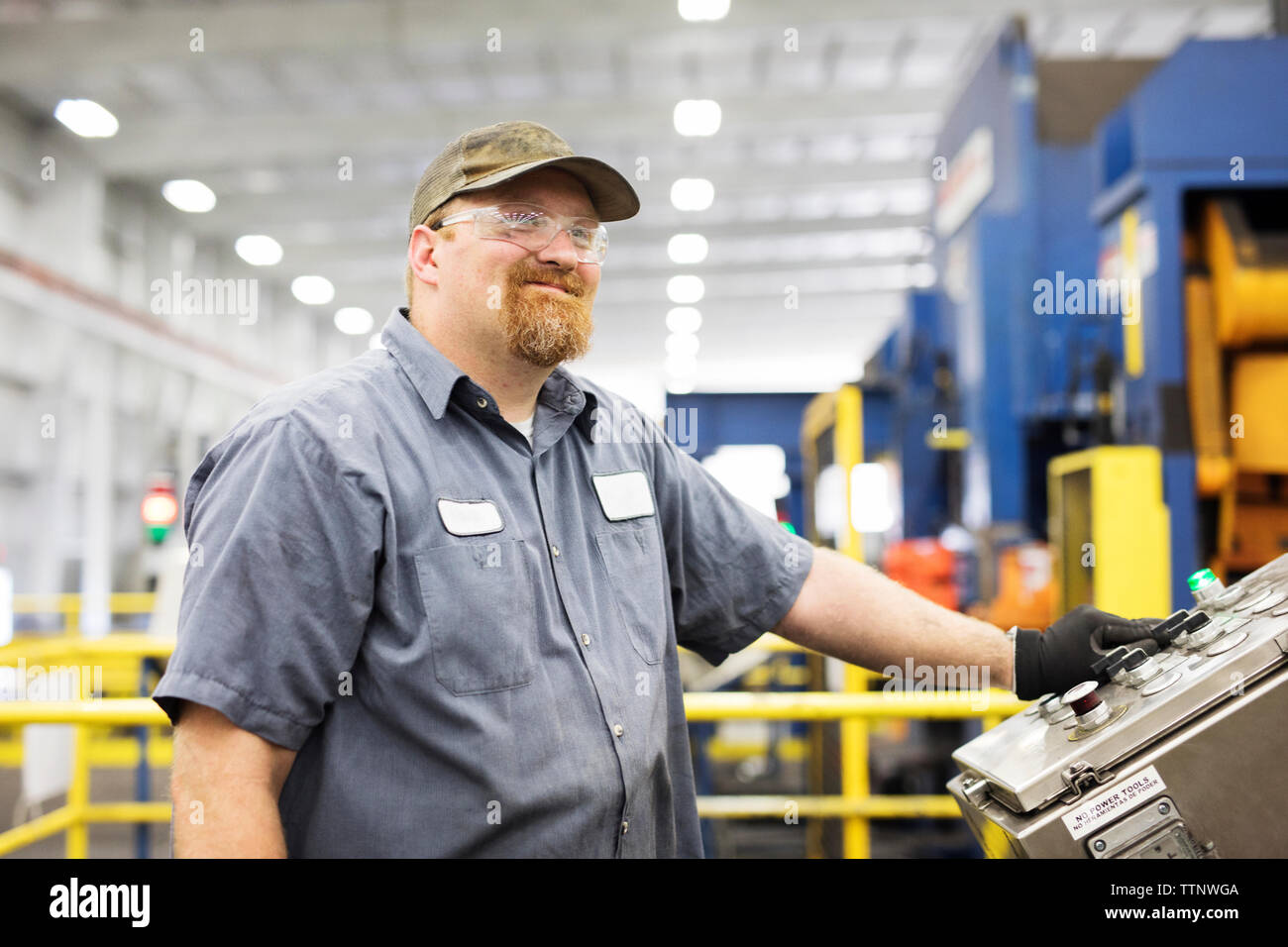 Smiling worker standing by machine at metal Steel industry Factory ...