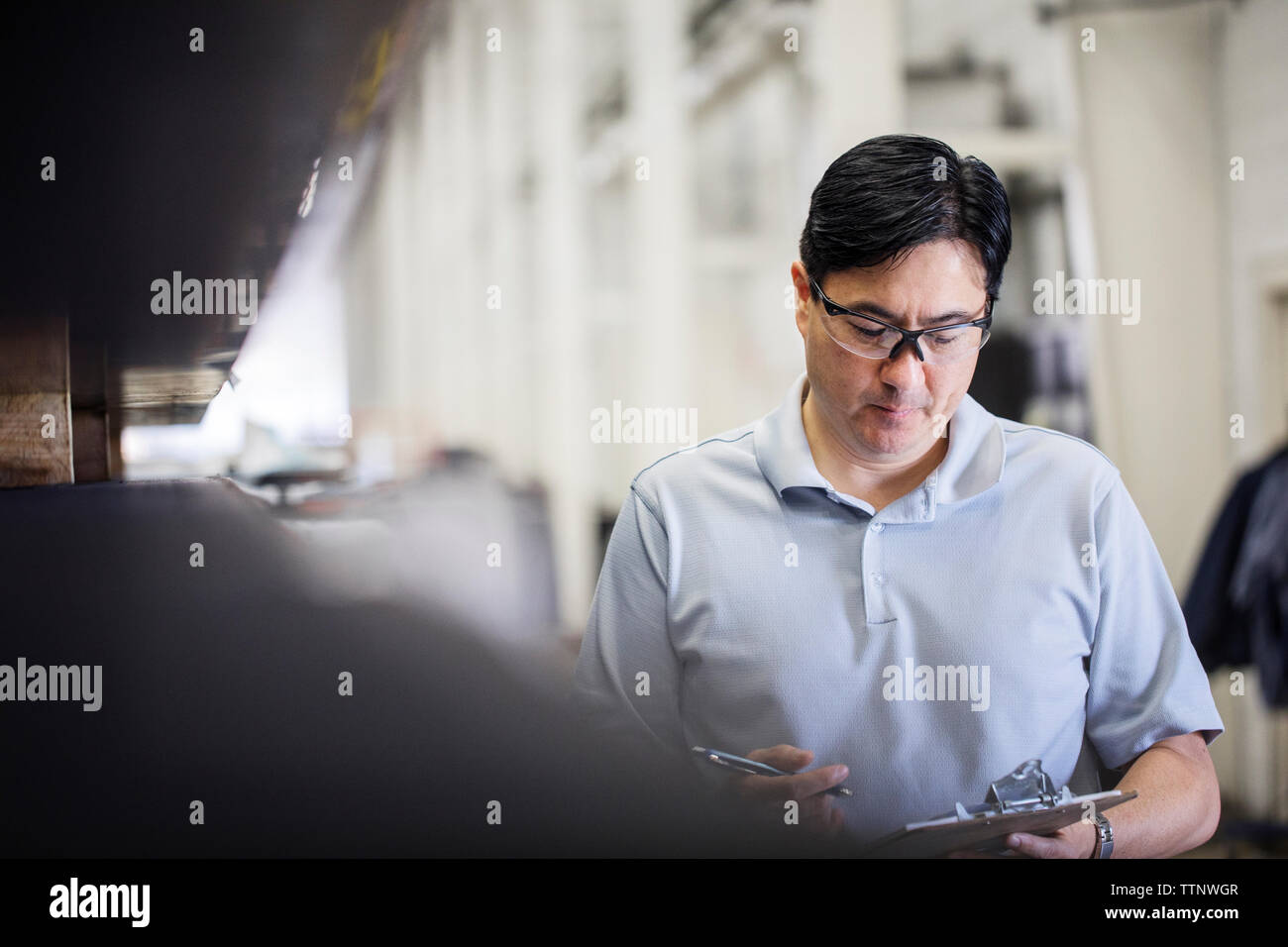 Serious supervisor writing on clipboard in warehouse Stock Photo - Alamy