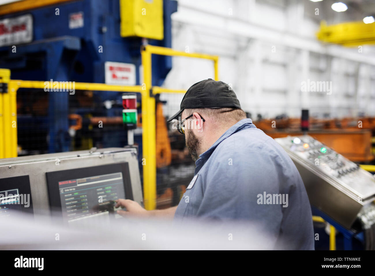Side view of worker using machine while working in metal Steel Mill ...