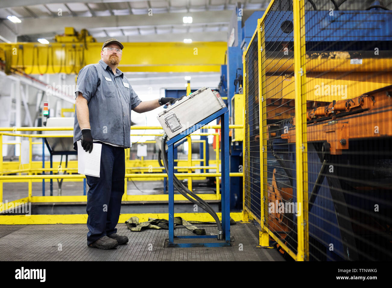 Full length of worker using machine while working in metal Steel Mill ...