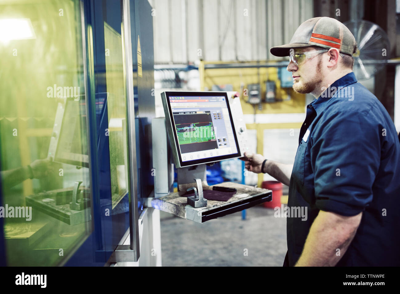 Side view of blue collar worker using desktop computer while working in ...