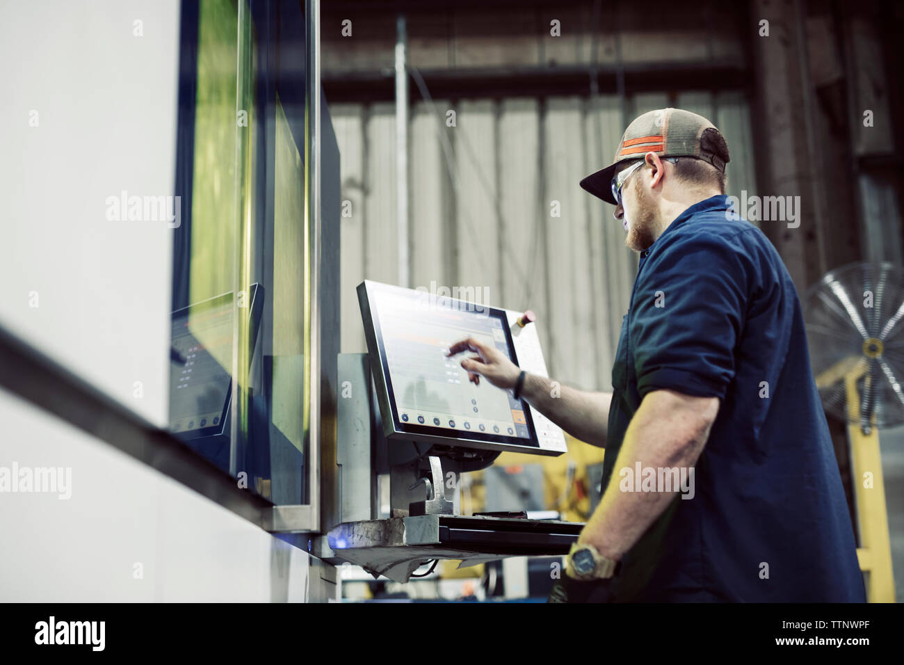 Low angle view of blue collar worker using desktop computer while ...