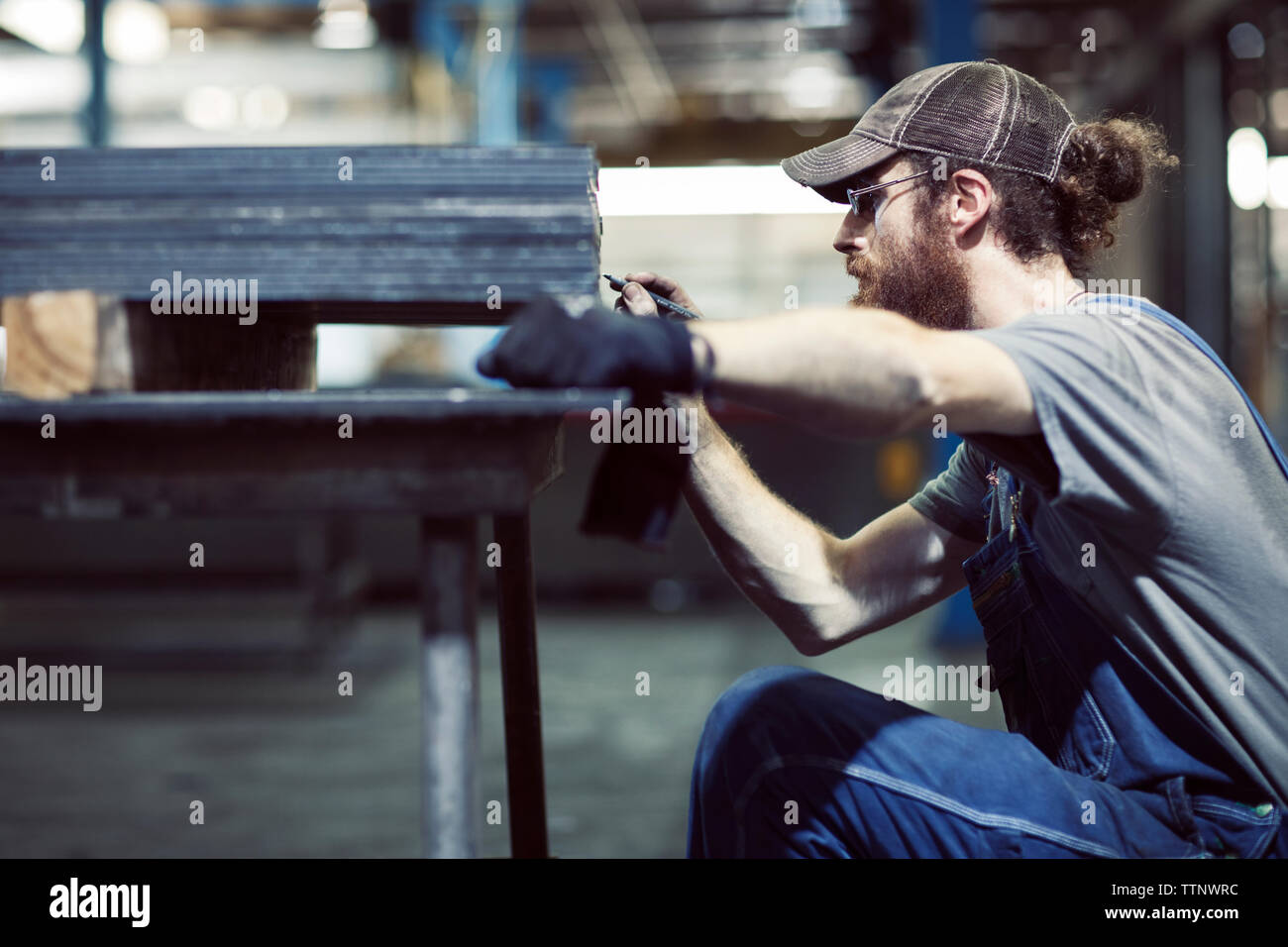 Side view of male worker working on steel sheets at industry Stock ...