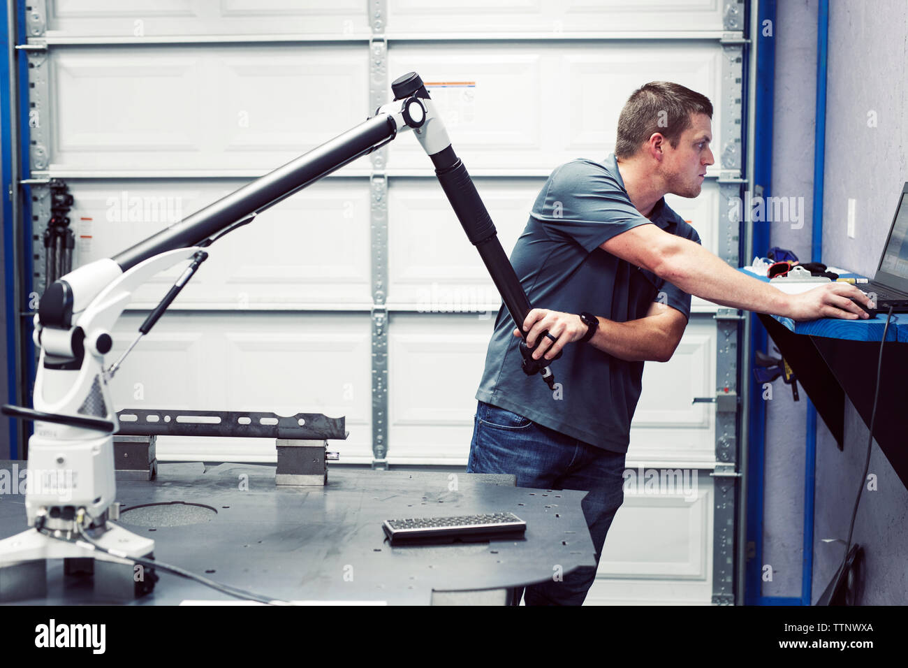 Serious worker using laptop while working on steel with equipment at ...