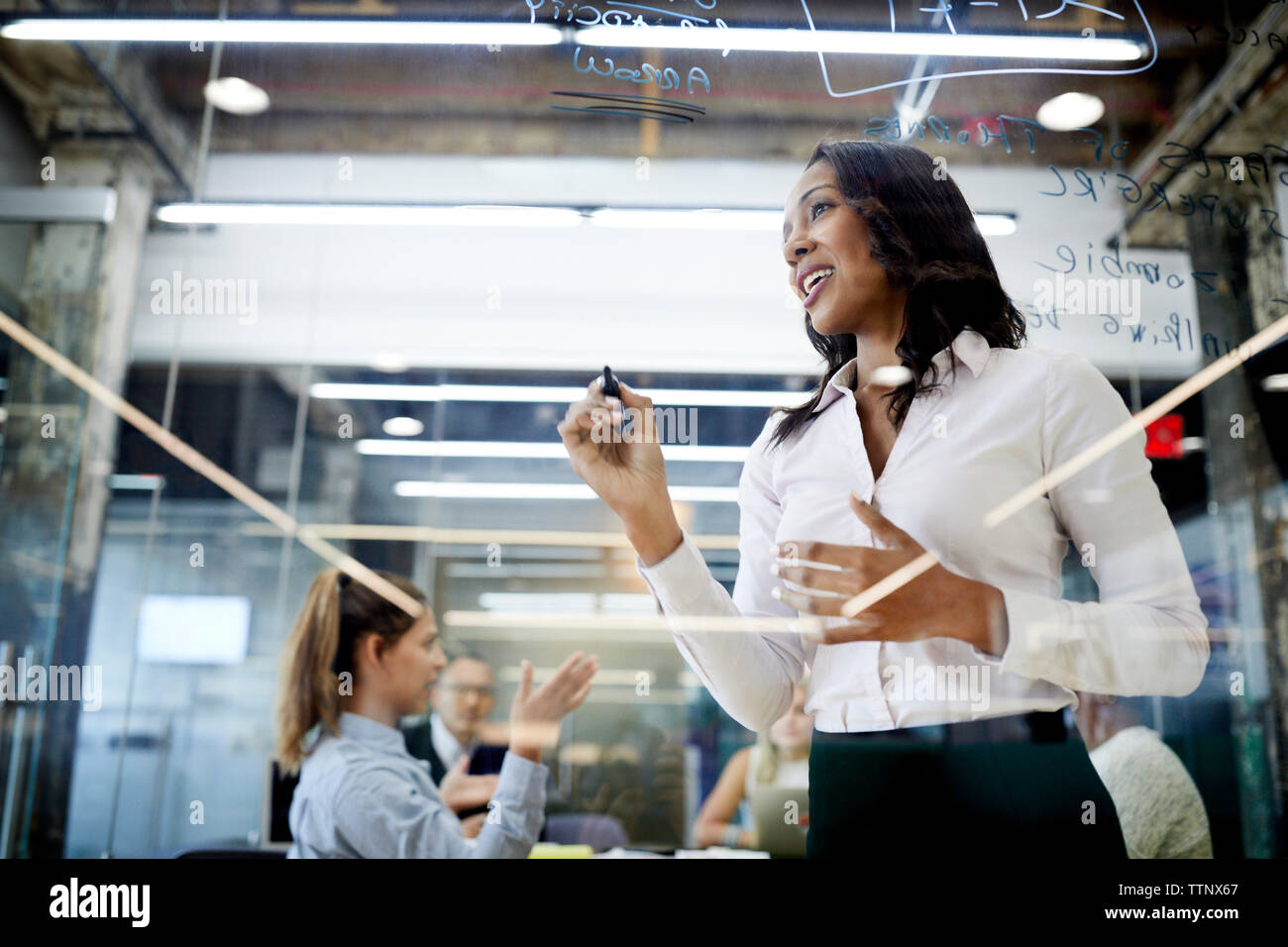 Low angle view of businesswoman writing on glass with felt tip pen ...