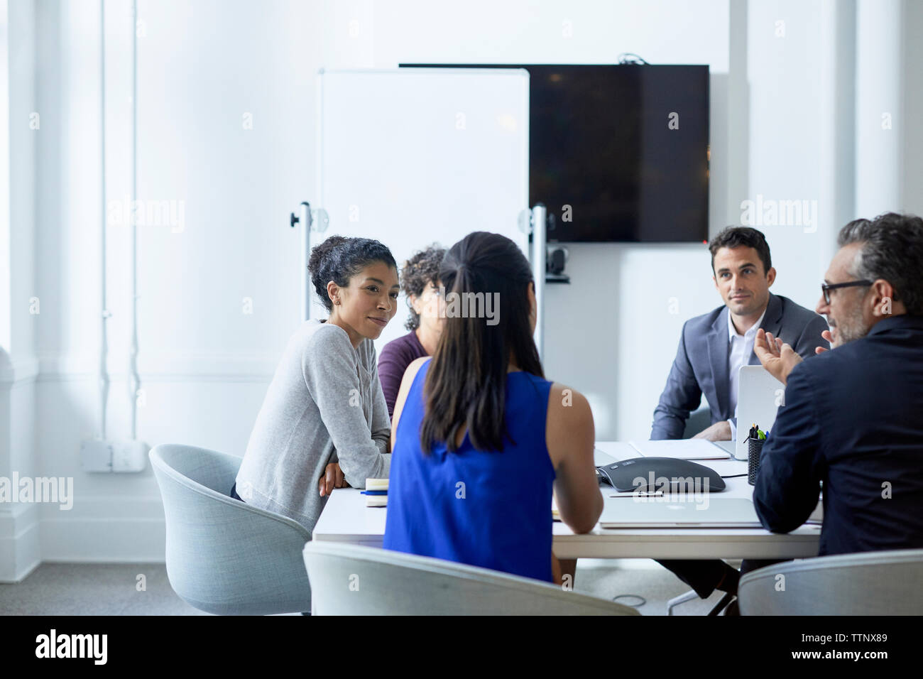 Confident business people discussing at conference table in office ...
