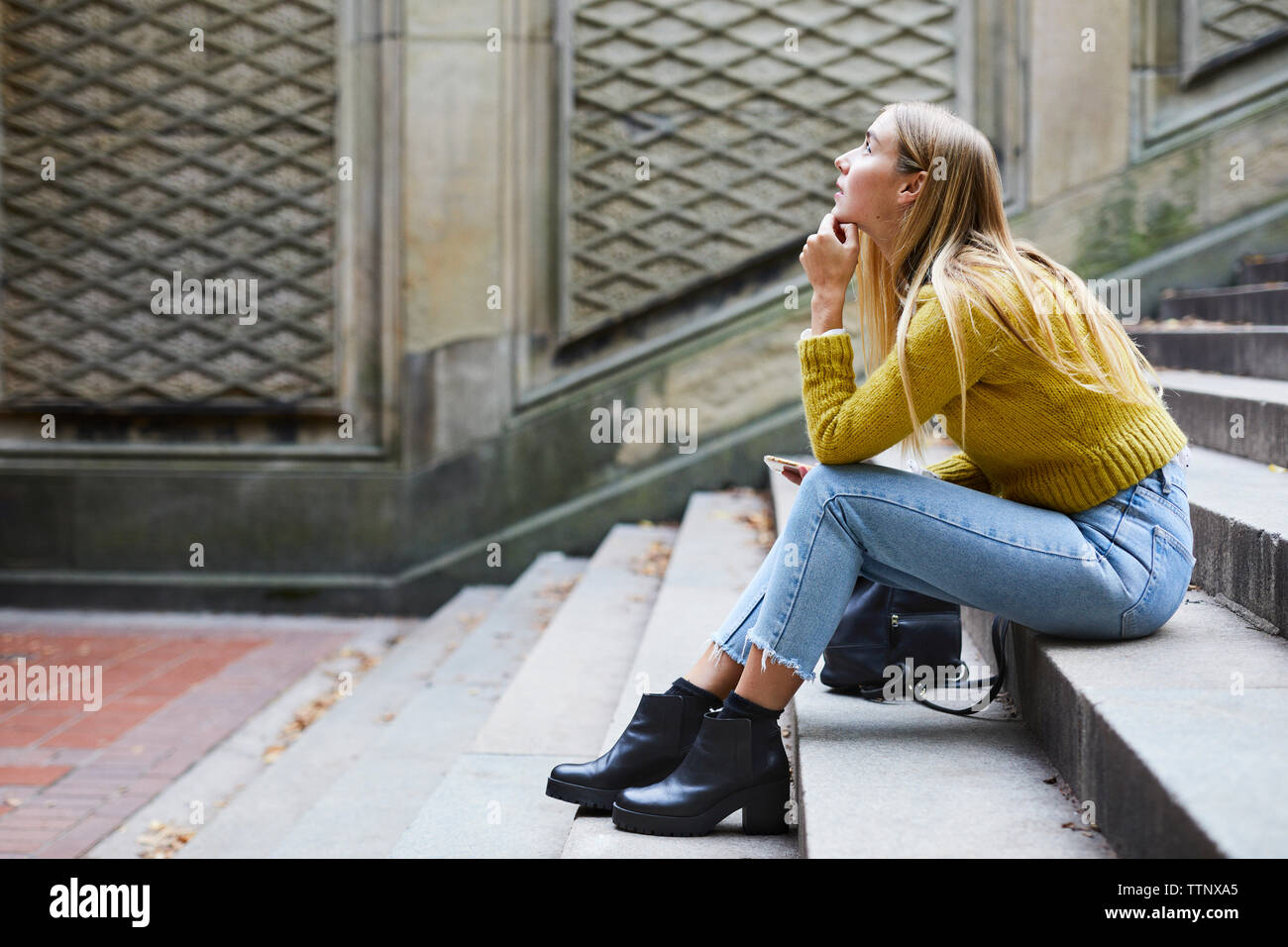 Side view of thoughtful woman sitting on steps at park Stock Photo - Alamy