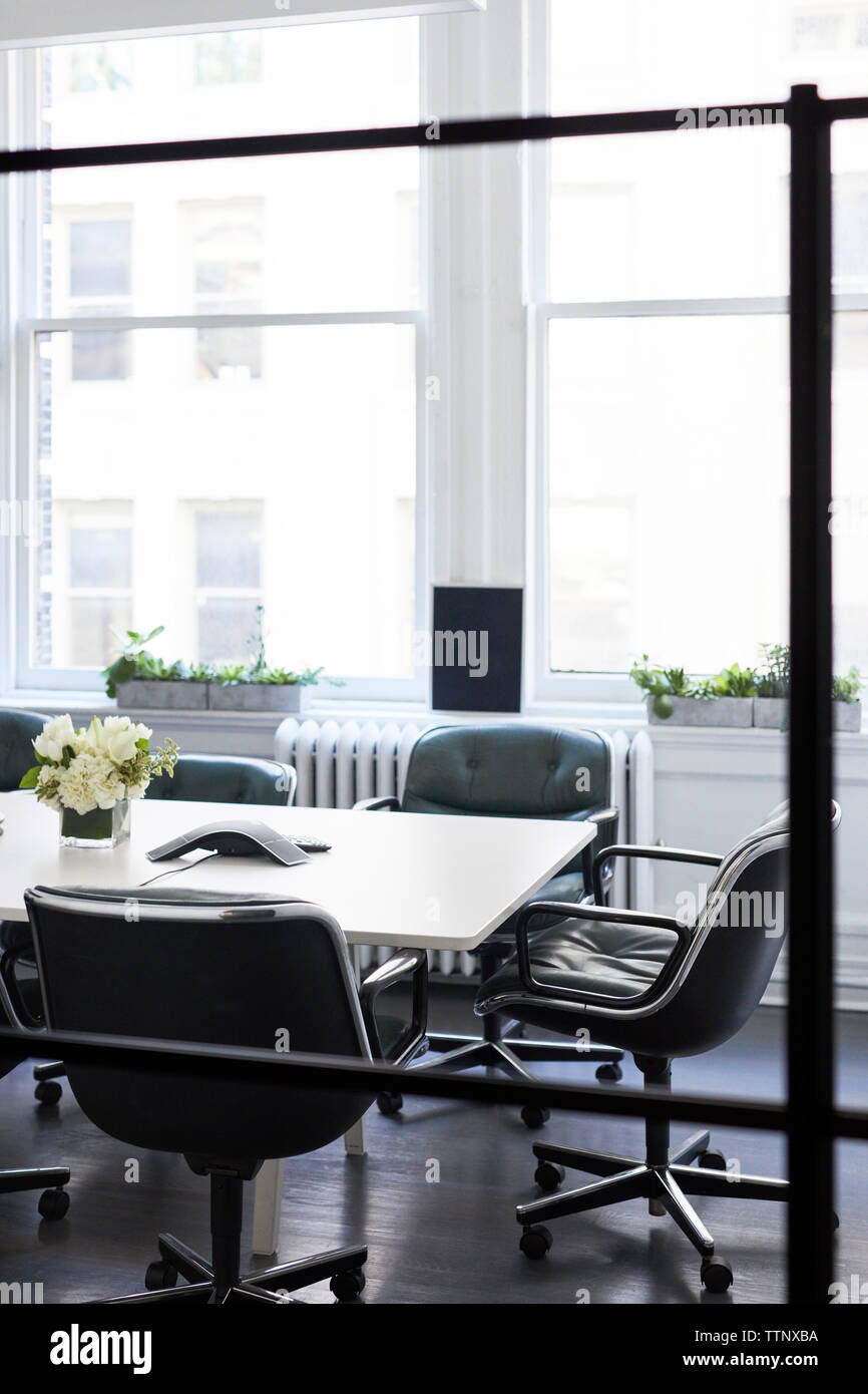 Empty chairs around conference table against windows in office Stock ...