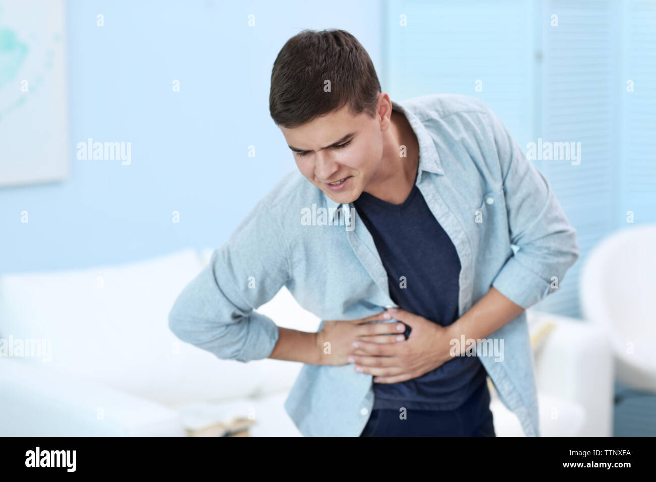 Unhappy man suffering from pain in tummy at home Stock Photo - Alamy
