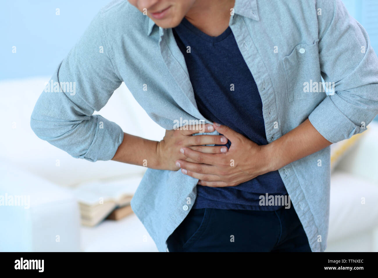 Unhappy man suffering from pain in tummy at home Stock Photo - Alamy