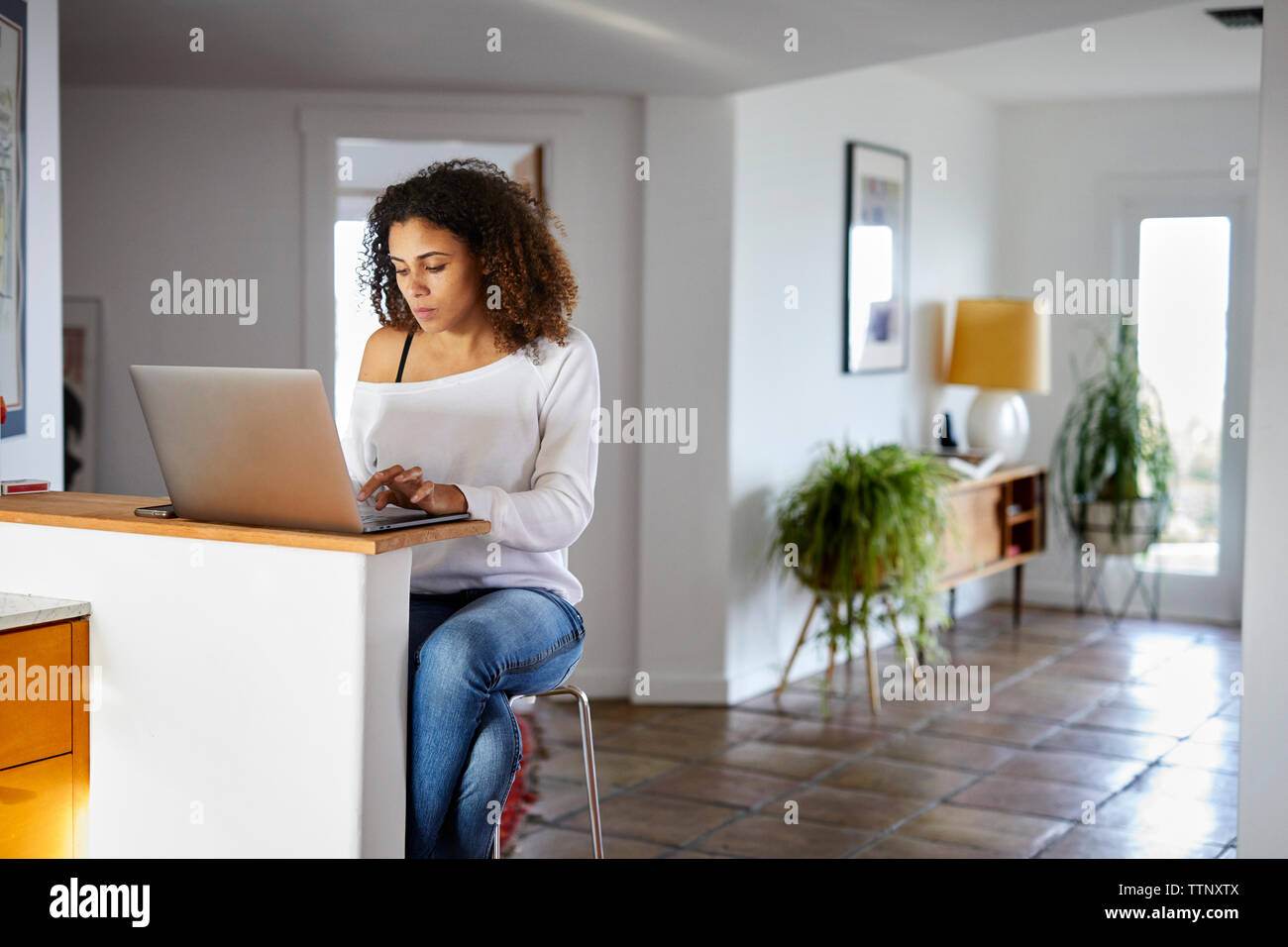 Woman using laptop computer while sitting on chair at home Stock Photo ...