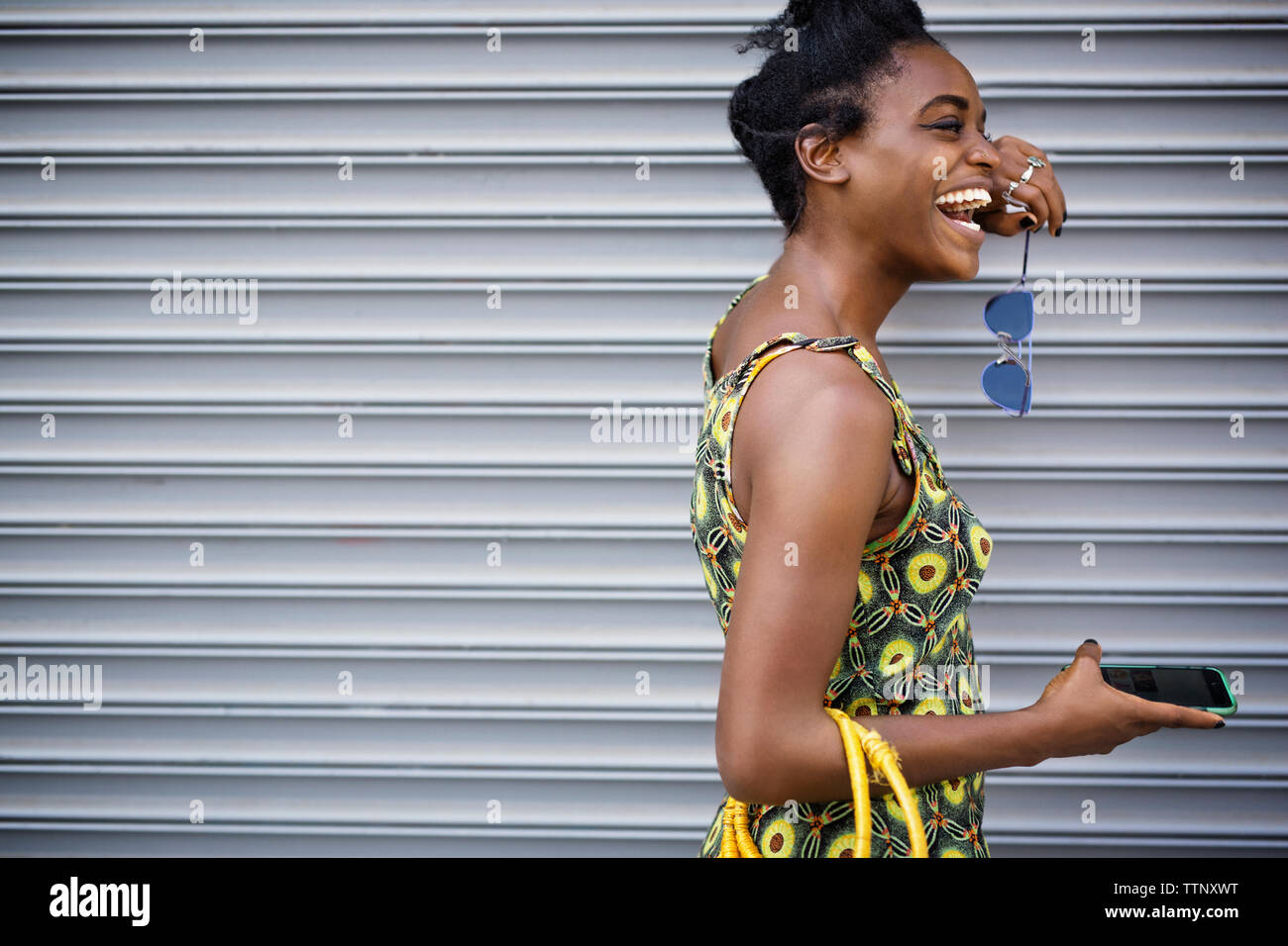 Woman laughing while standing against shutter Stock Photo - Alamy