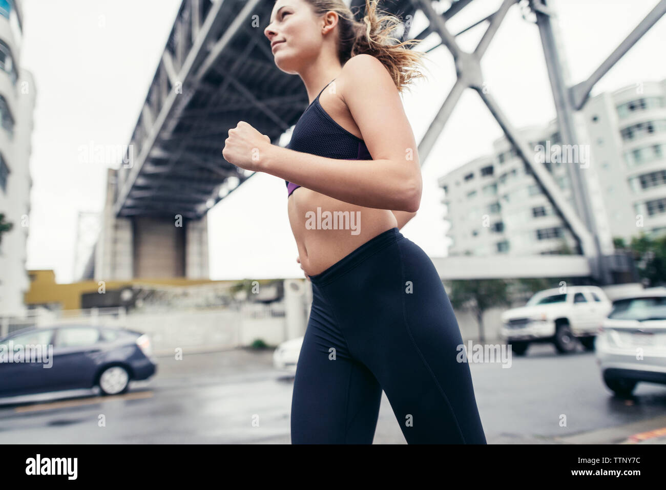 Low angle view of determined female athlete running on street under ...