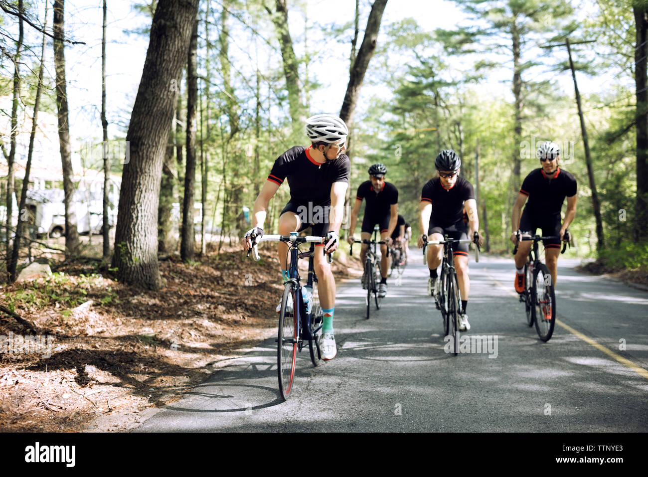 Determined male cyclists riding bicycles on country road Stock Photo ...