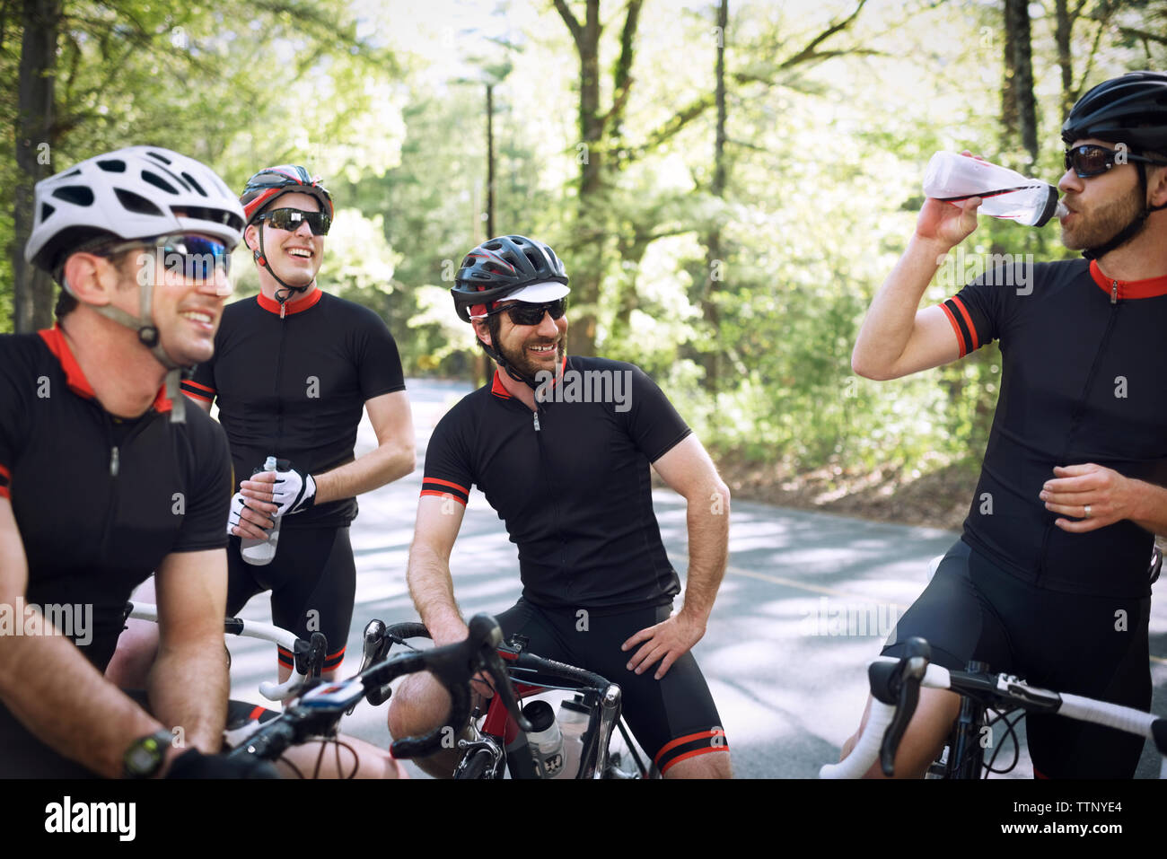 Happy male cyclists relaxing on road Stock Photo - Alamy