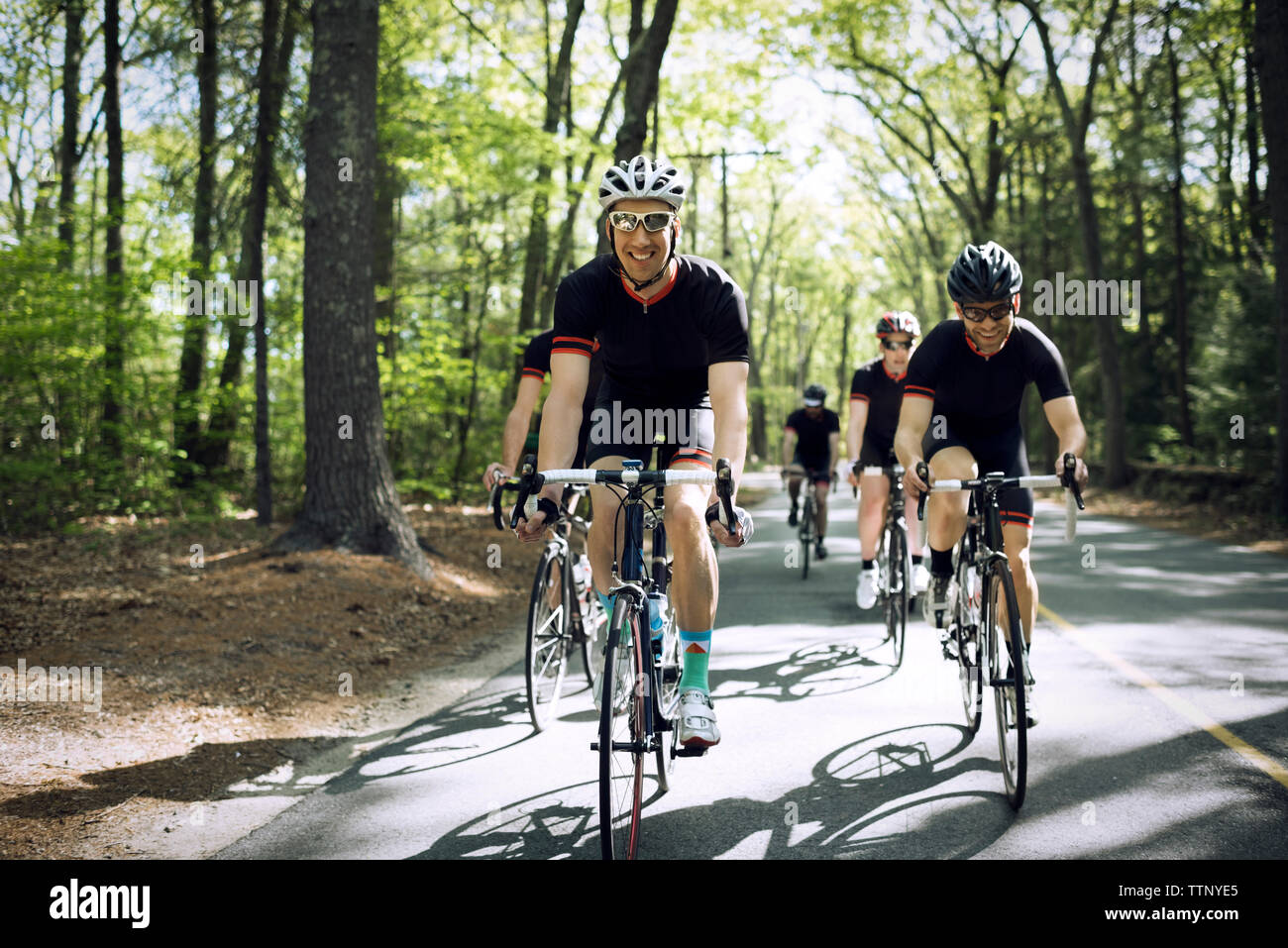 Smiling male cyclist riding bicycle with friends on country road Stock ...