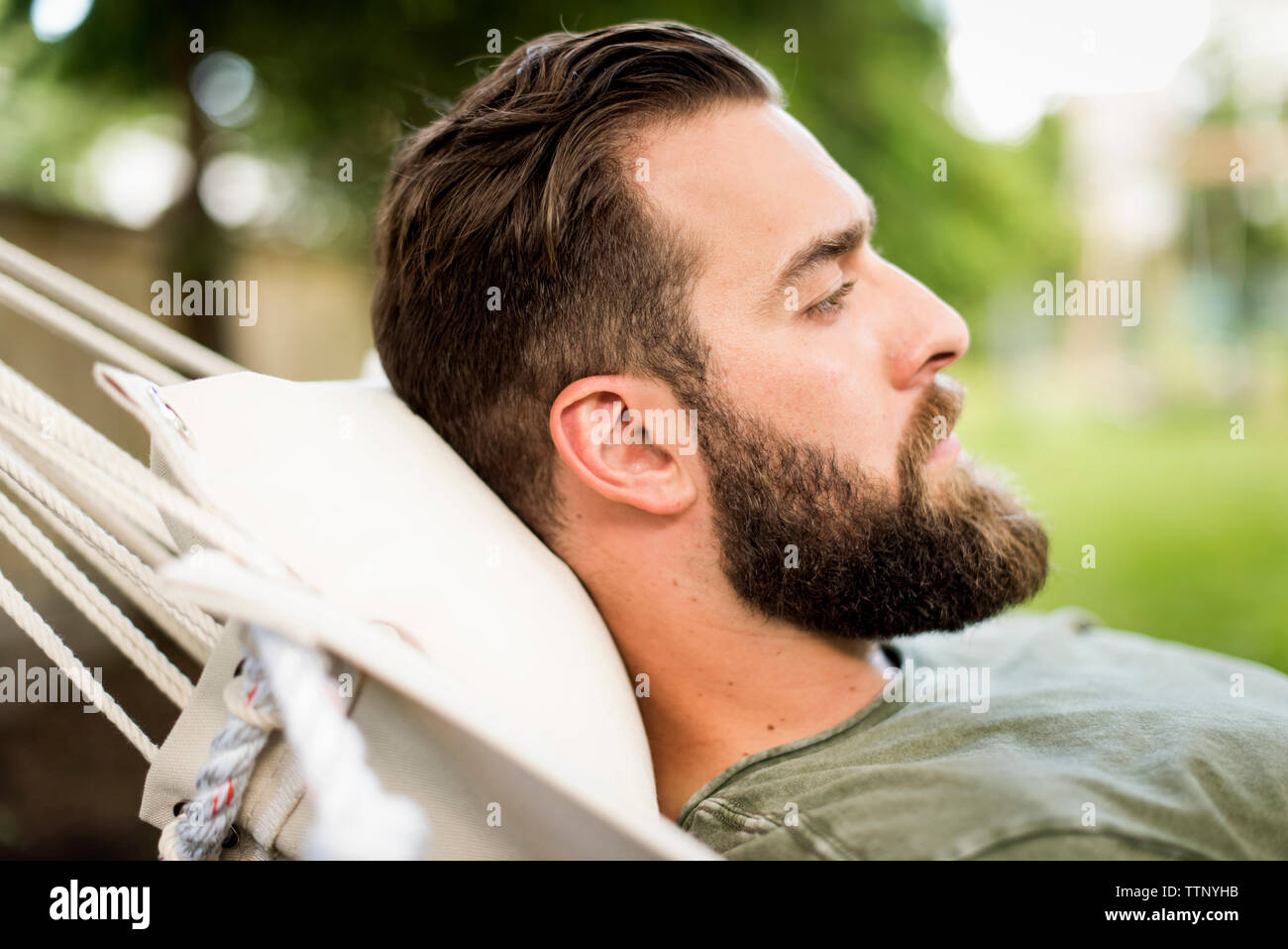 Side view of man relaxing on hammock at yard Stock Photo - Alamy