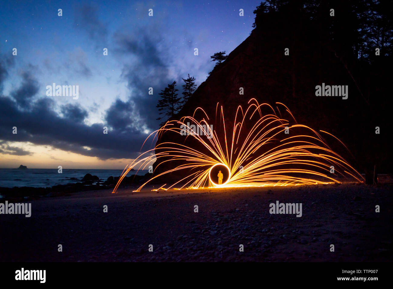 Man spinning wire wool on field at night Stock Photo - Alamy