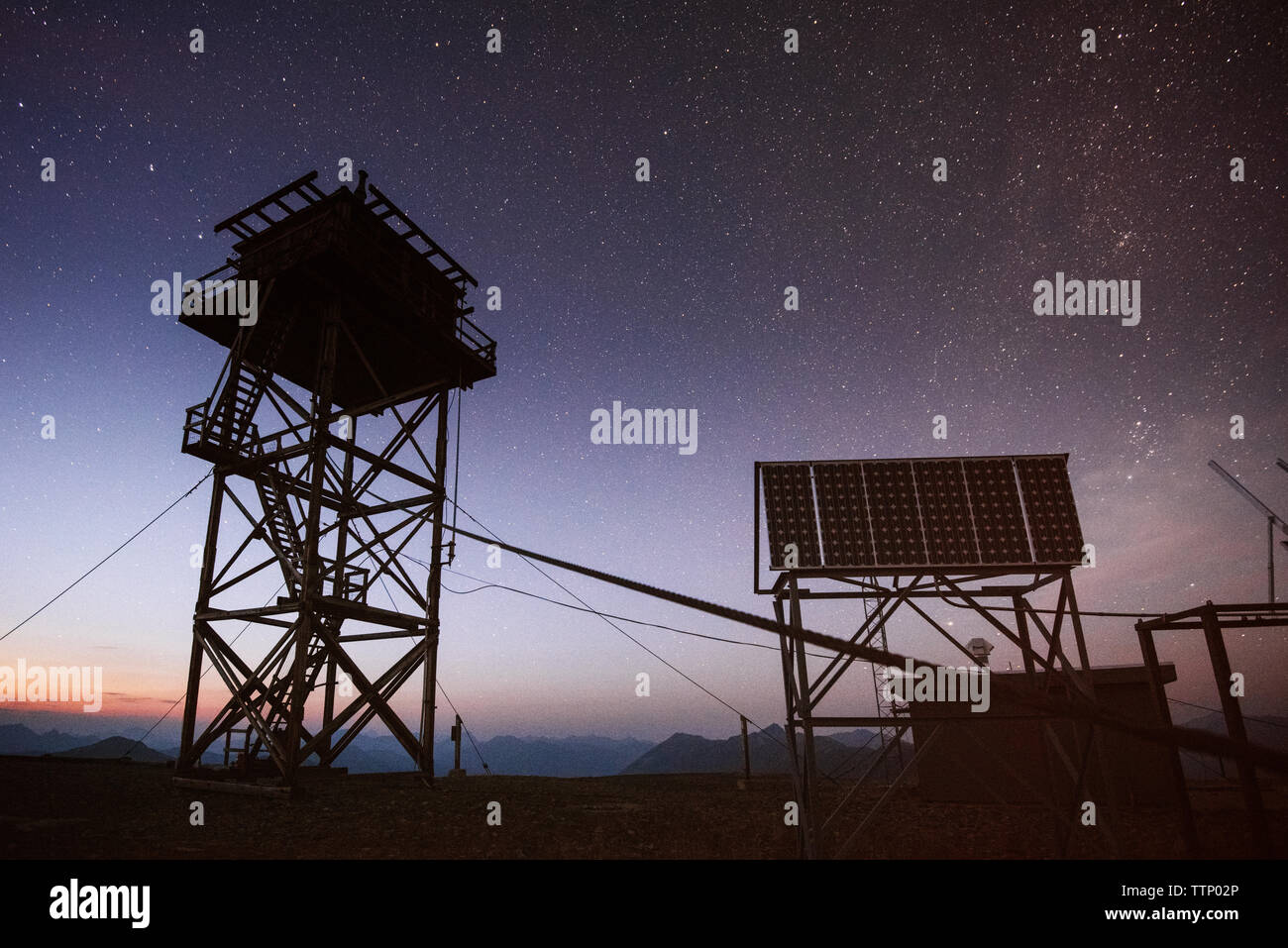 Silhouette lookout tower and billboard against starry sky at night ...
