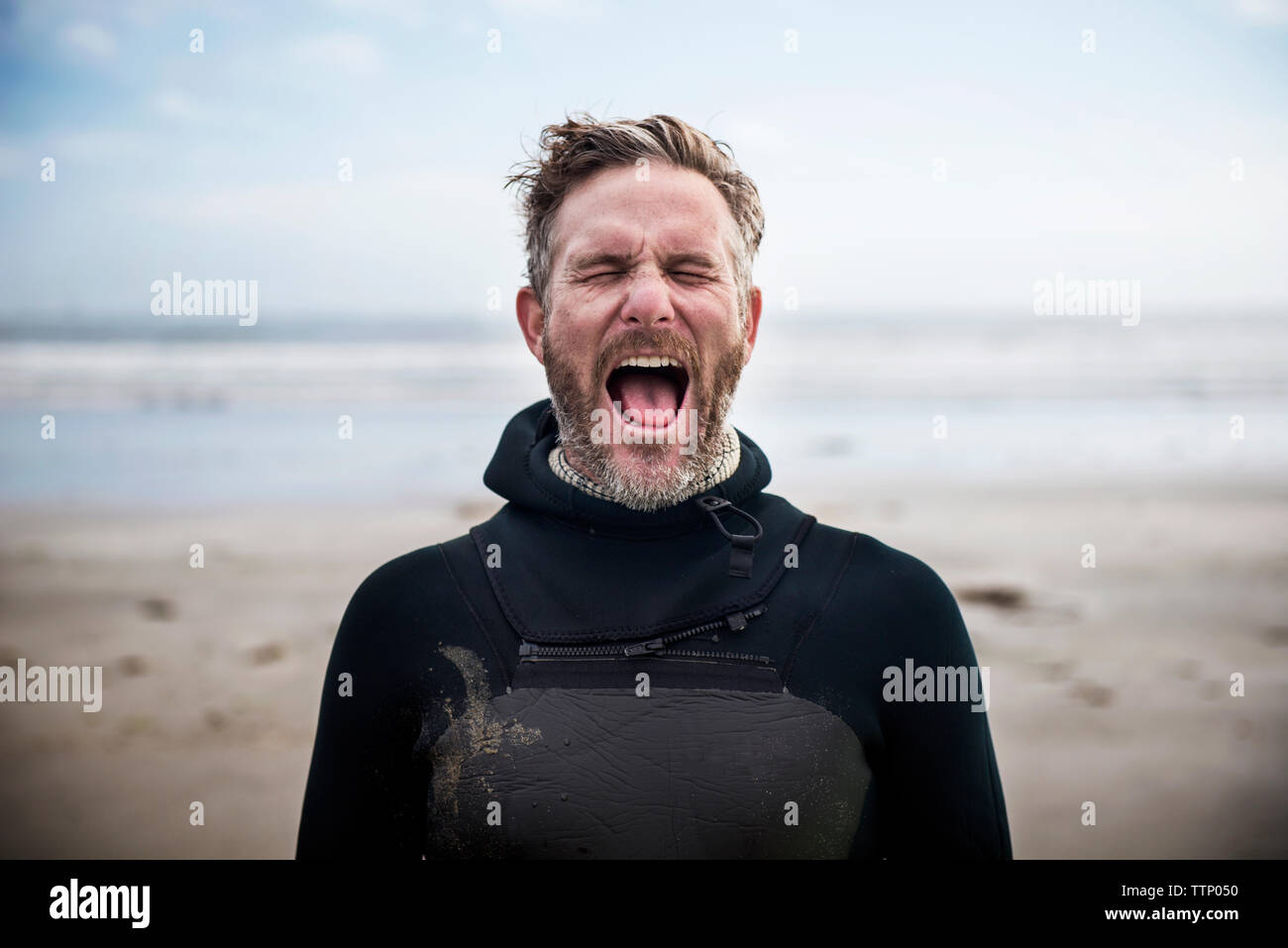 Male surfer screaming while standing at beach Stock Photo - Alamy