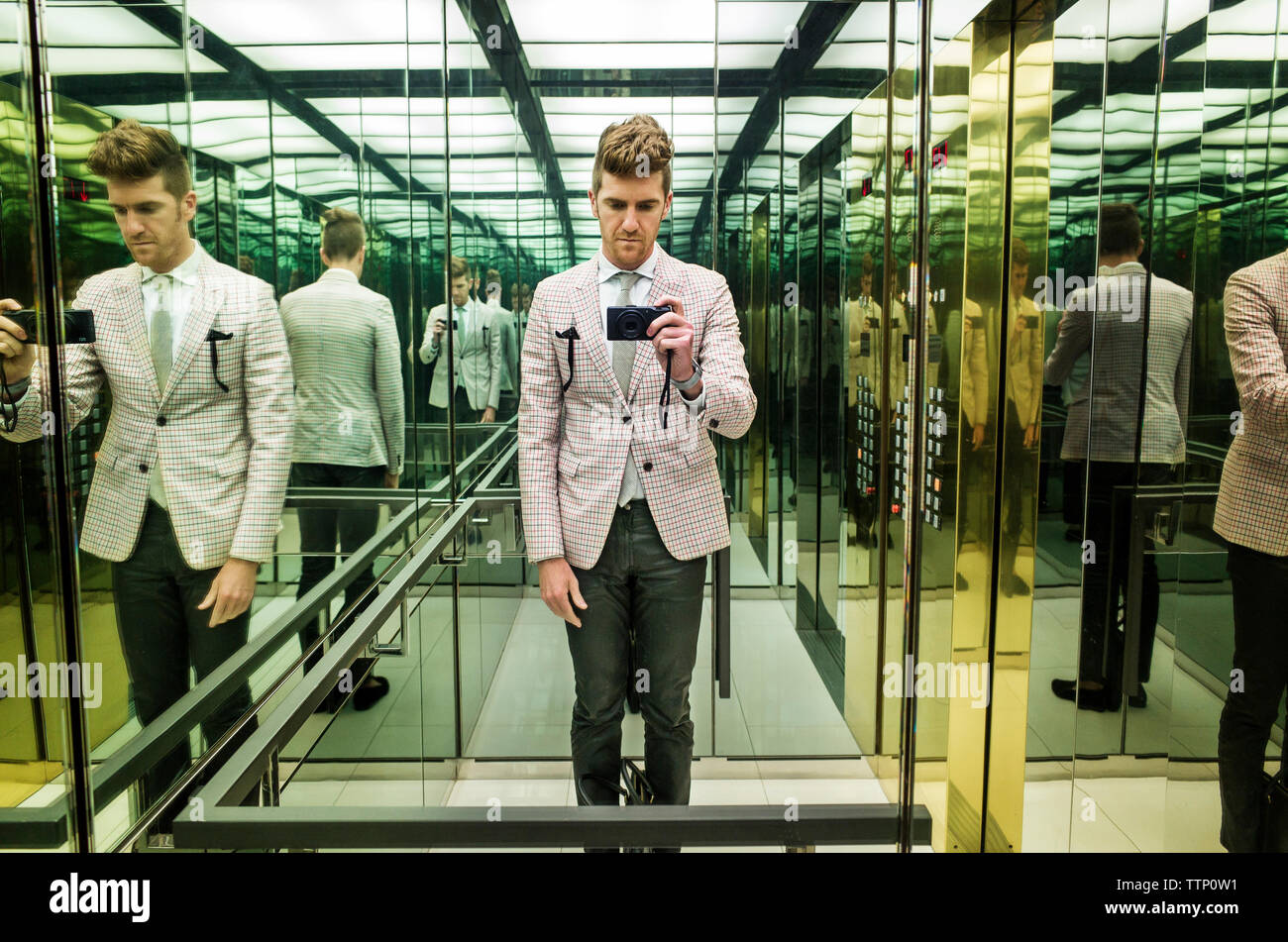 Reflection of man photographing with camera in mirror at elevator Stock ...