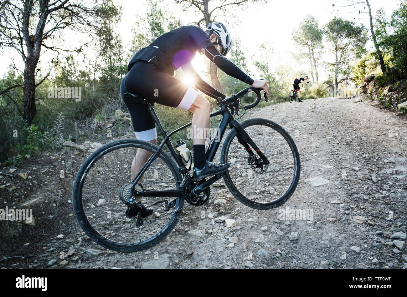 Side view of man cycling on dirt road Stock Photo - Alamy