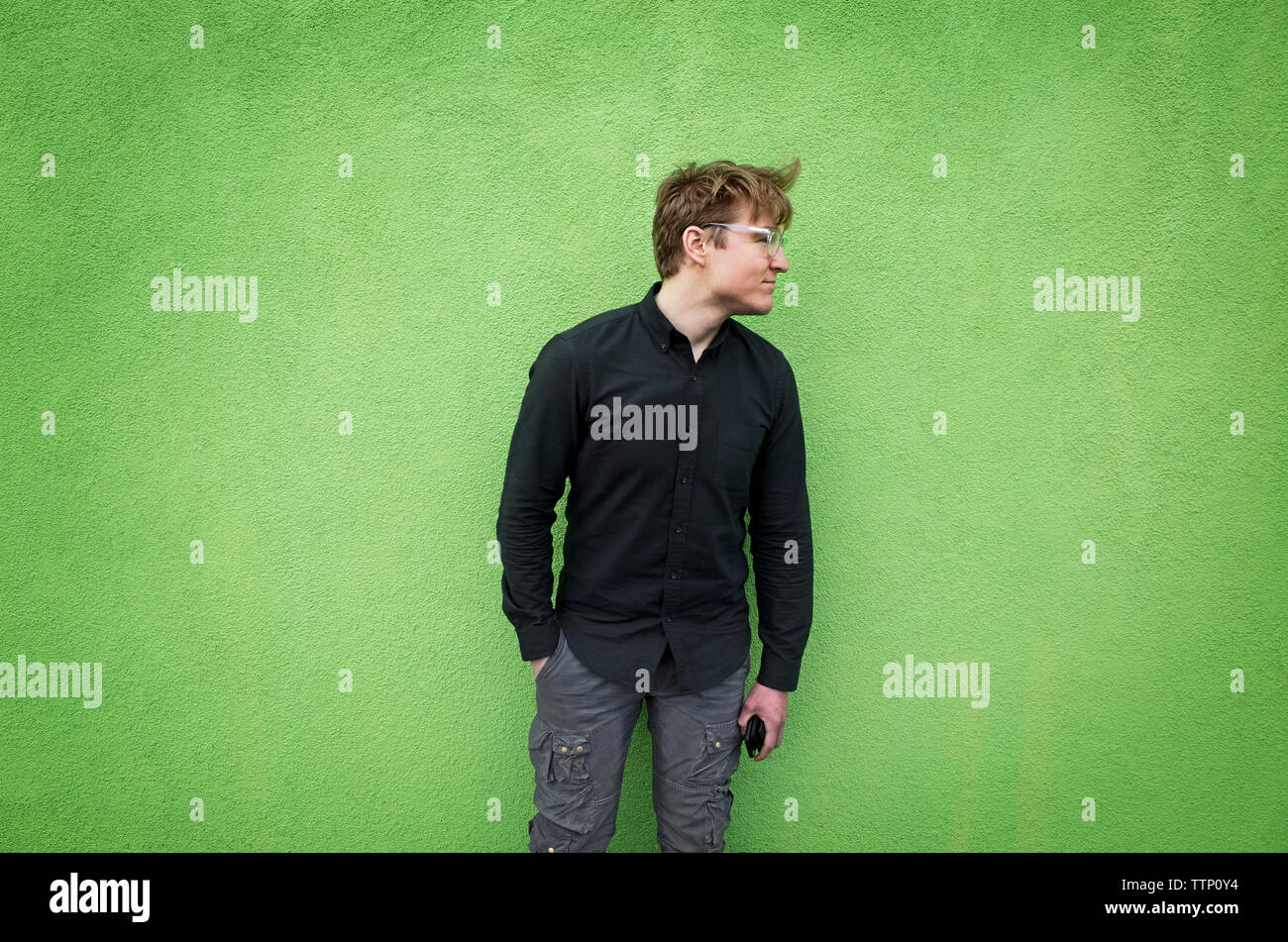 Man standing against green wall Stock Photo - Alamy