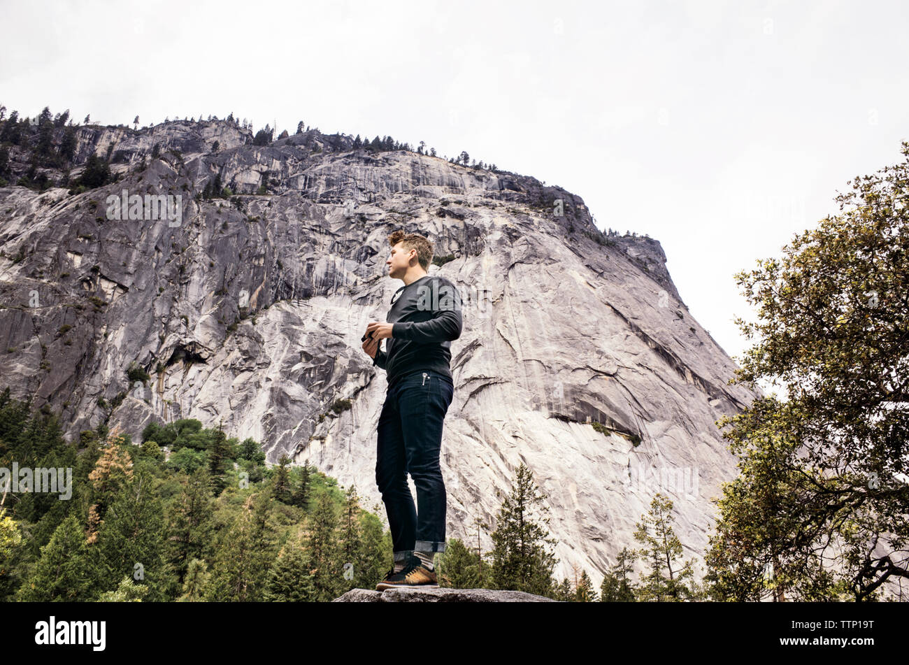 Low angle view of man standing against mountain Stock Photo - Alamy