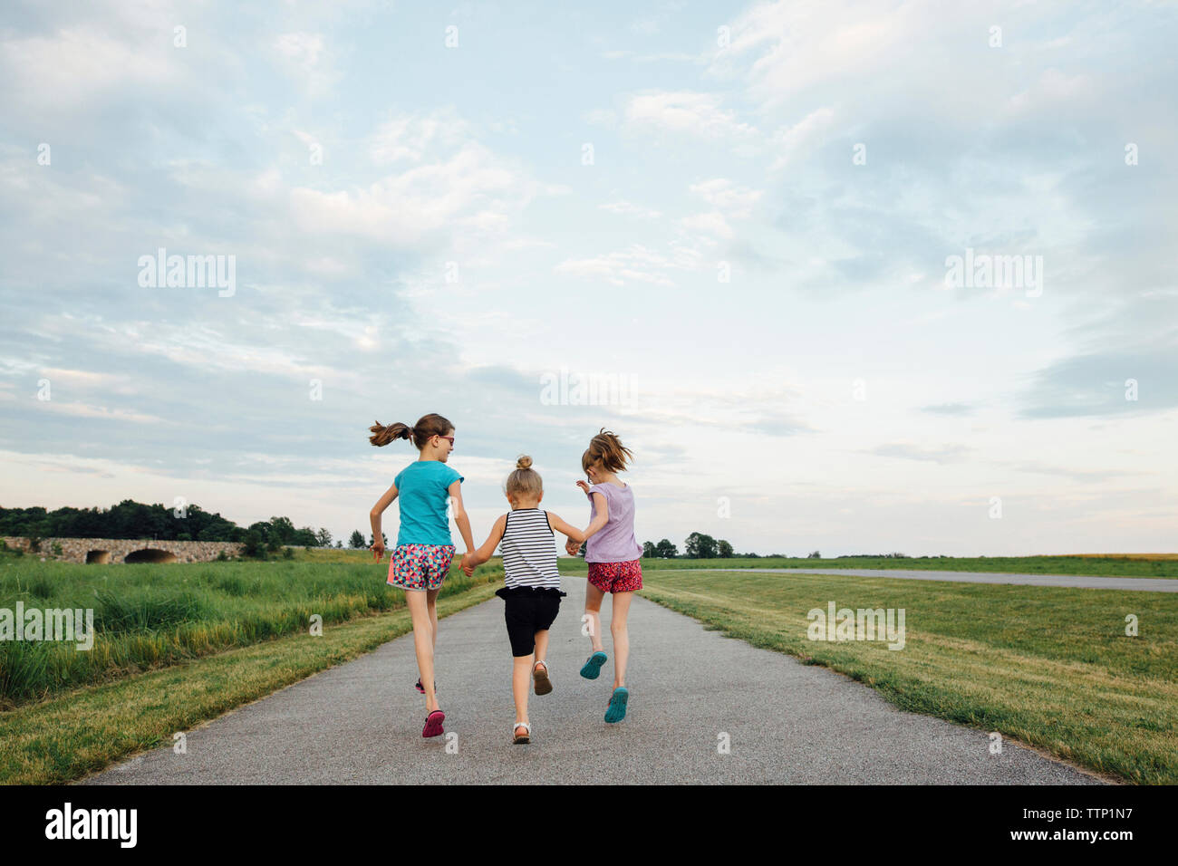 Three girls holding hands hi-res stock photography and images - Alamy