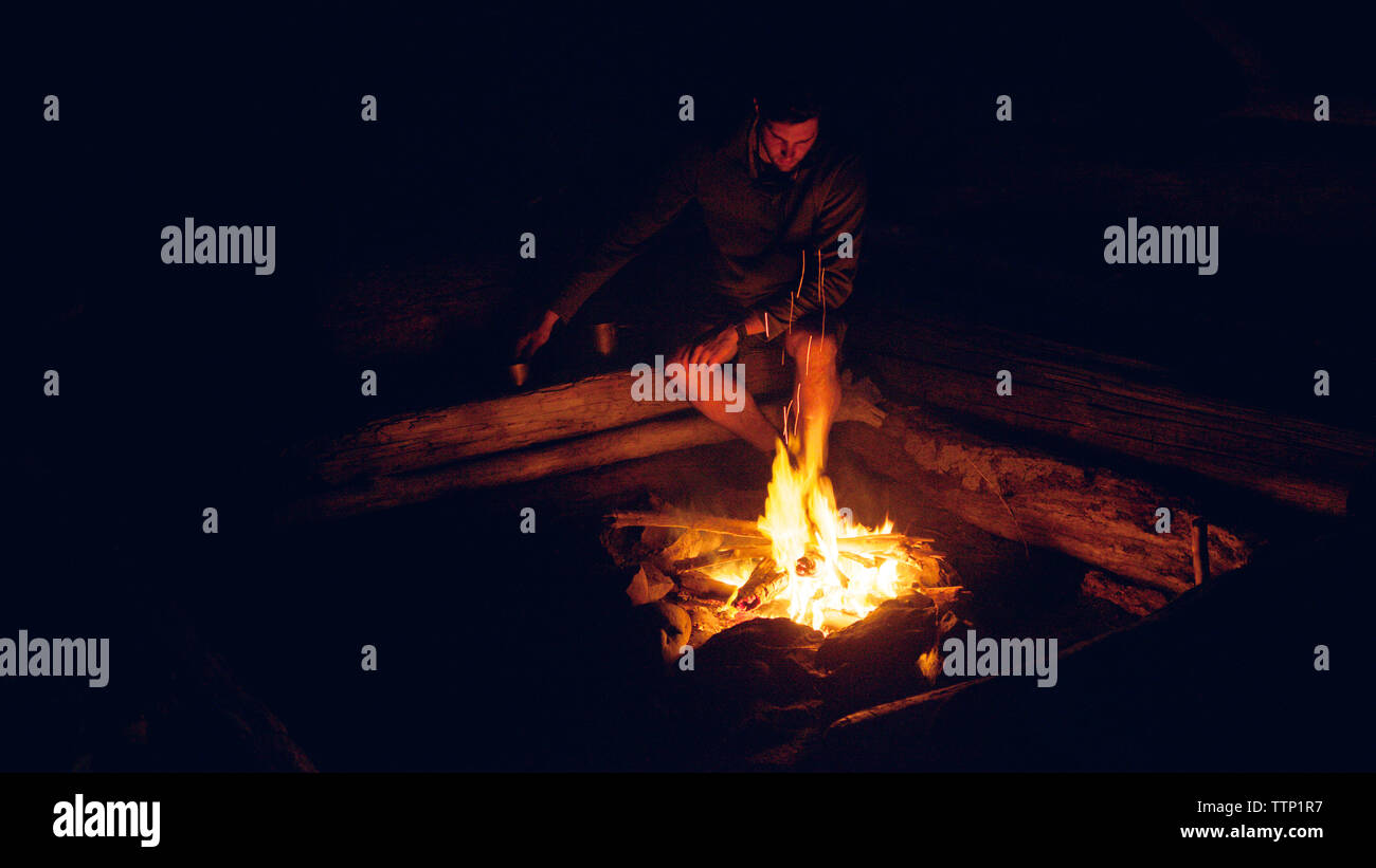 Man sitting by bonfire at night Stock Photo - Alamy
