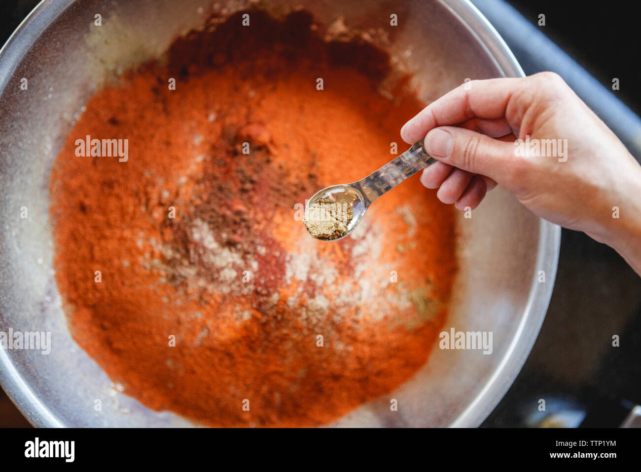 Overhead view of woman mixing spices in container Stock Photo - Alamy