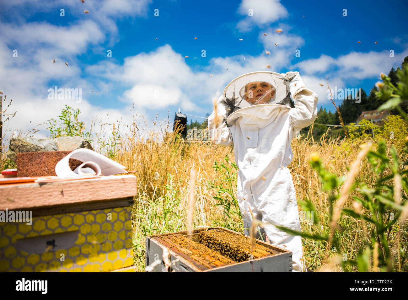 Boy adjusting hat while standing on field against cloudy sky Stock ...