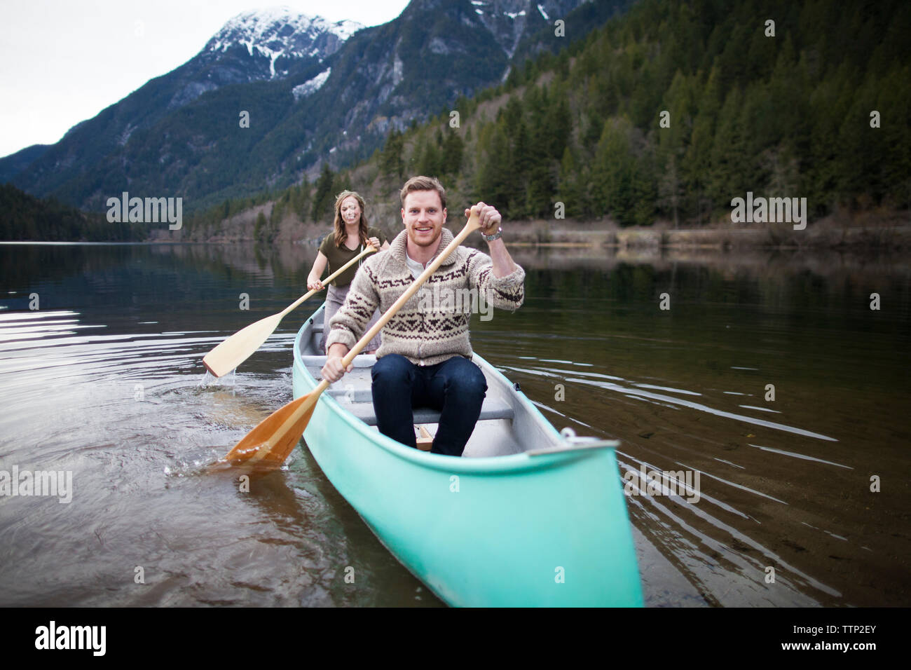 Happy young couple canoeing on lake against mountains Stock Photo - Alamy