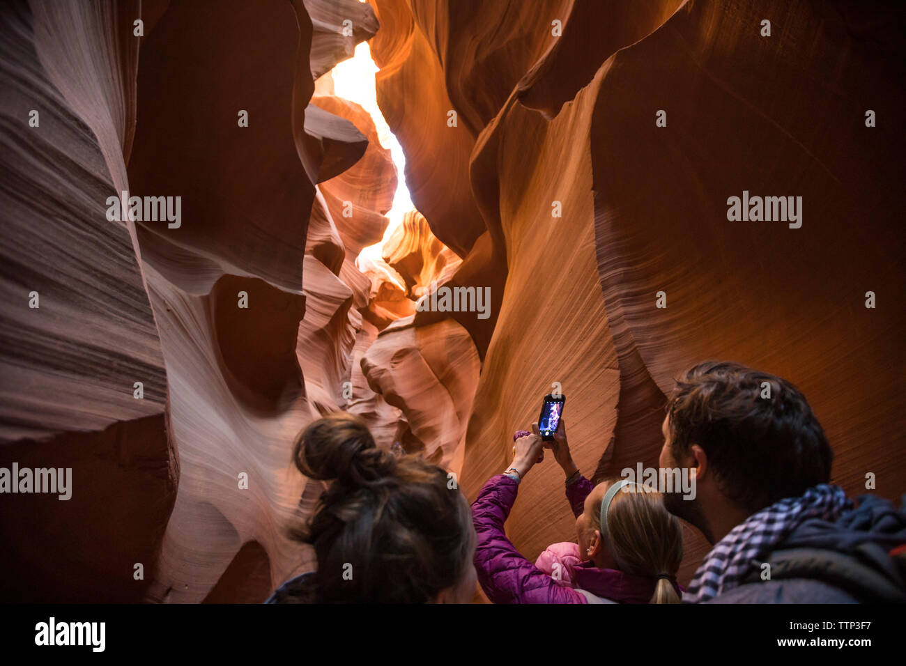 Woman photographing rock formations while standing with friends at Page ...