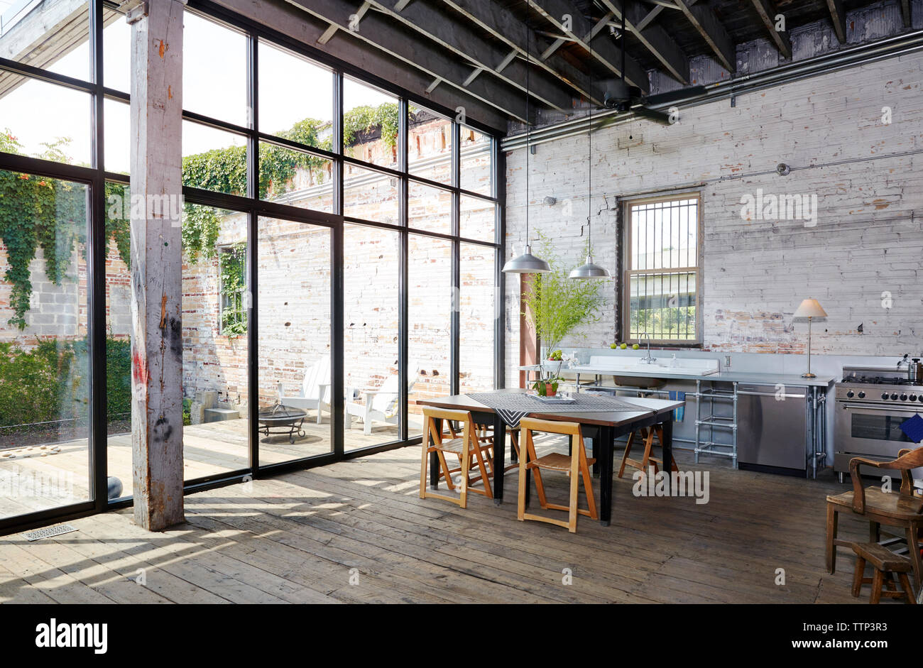 Table and chairs by large glass wall at home Stock Photo - Alamy