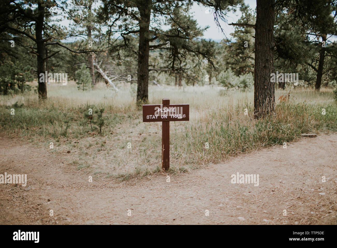 Warning signboard on field by dirt road at forest Stock Photo - Alamy