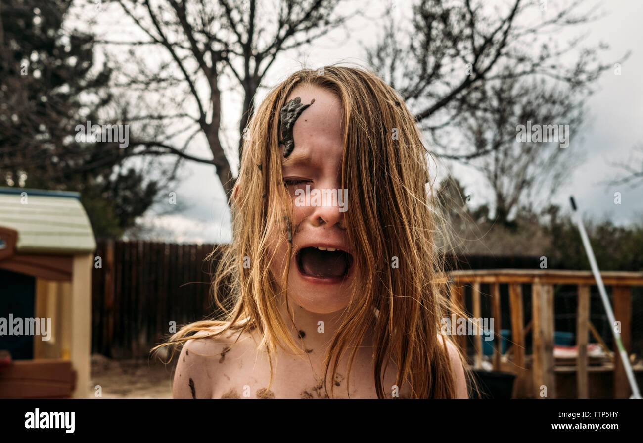 Close Up Of Girl Crying And Screaming With Mud On Face At Backyard