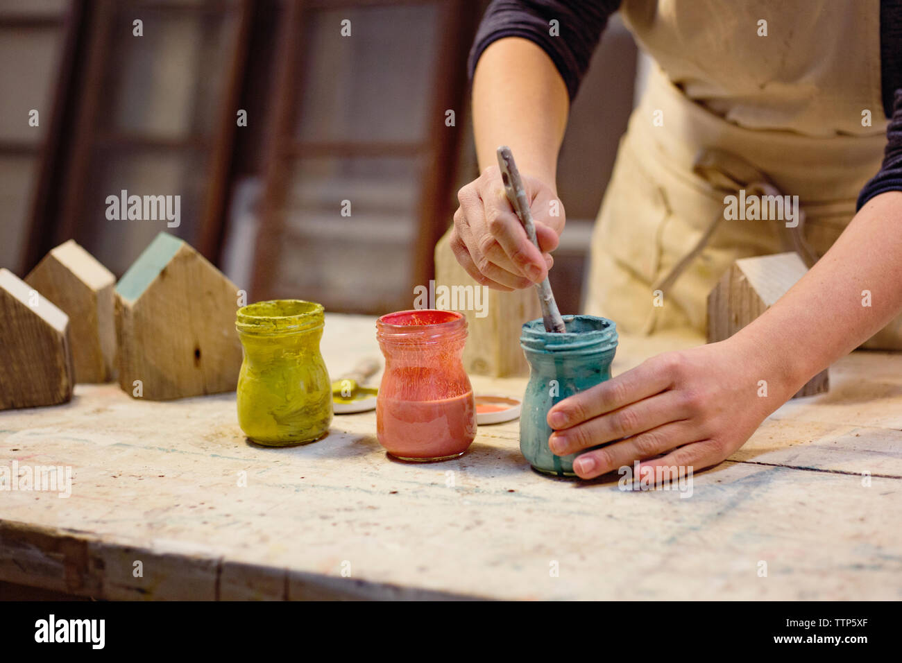 Midsection of carpenter coloring wooden model houses in workshop Stock ...