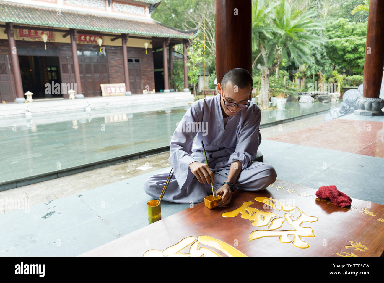happy young monk in temple painting on a board Stock Photo - Alamy