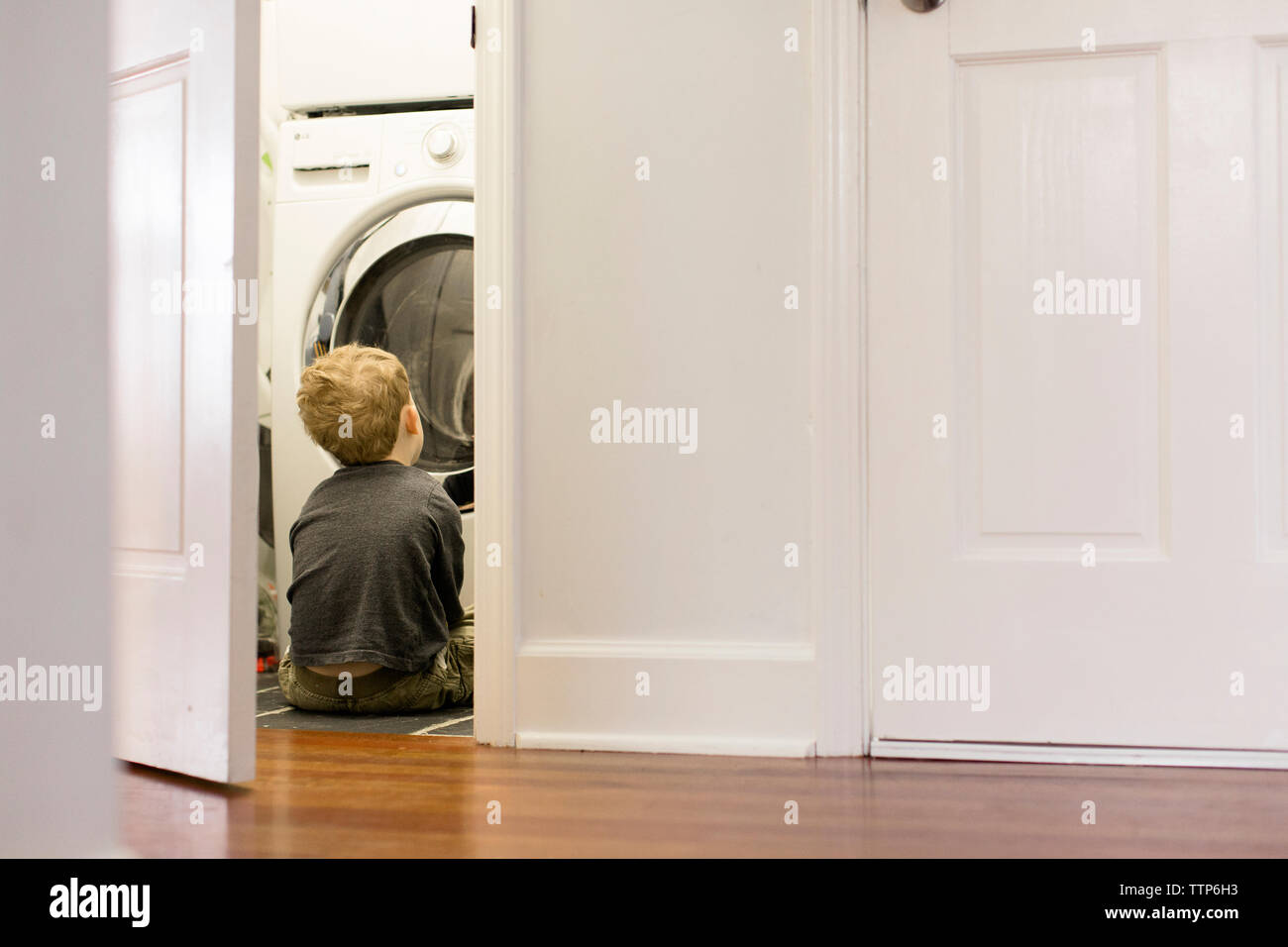 Boy looking at washing machine seen through doorway Stock Photo - Alamy