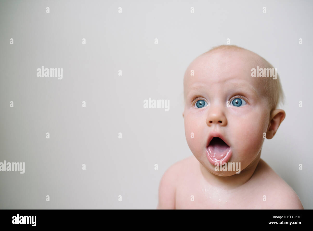Cute baby girl with mouth open against wall Stock Photo - Alamy